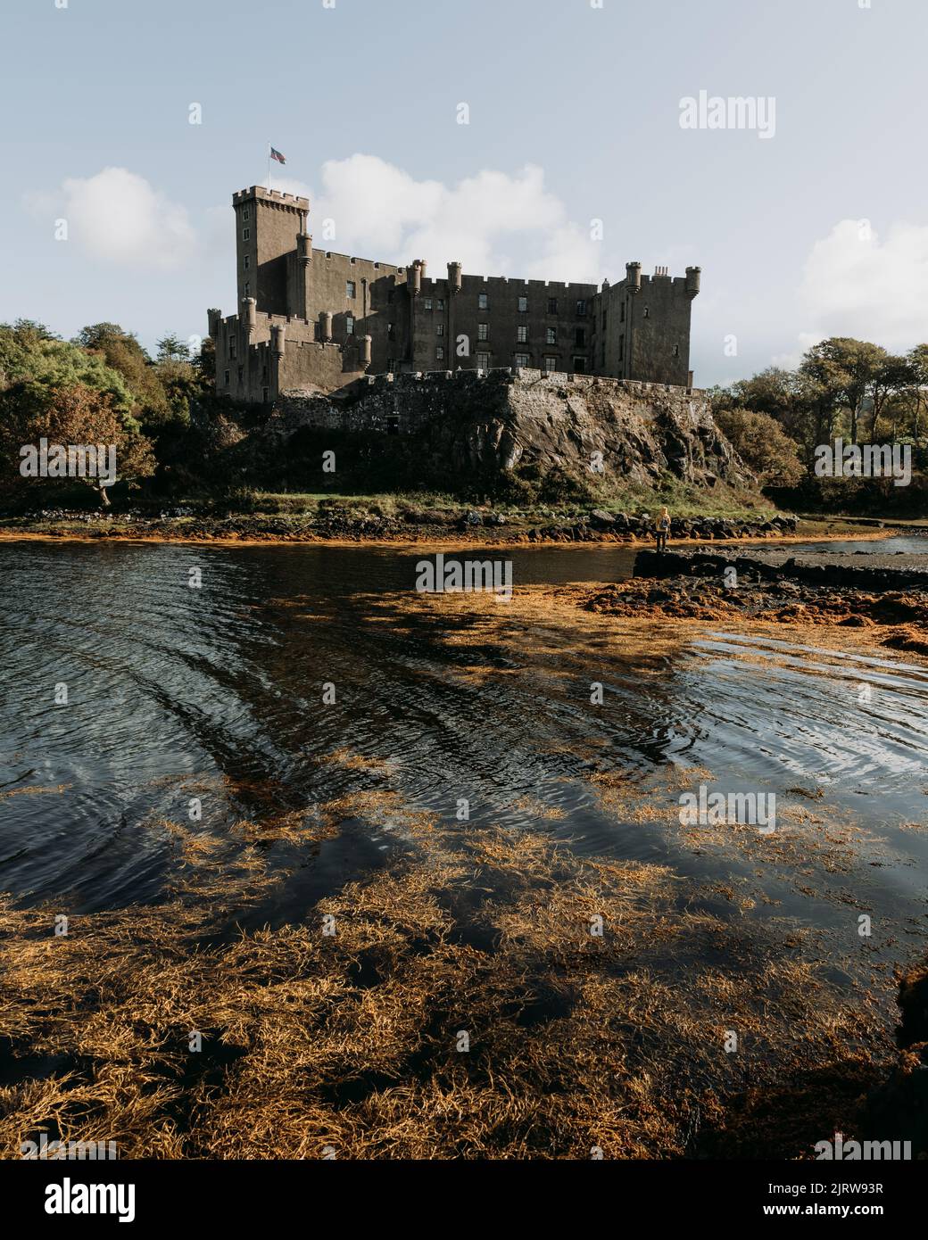The vertical view of the Dunvegan castle on the riverbank under the ...