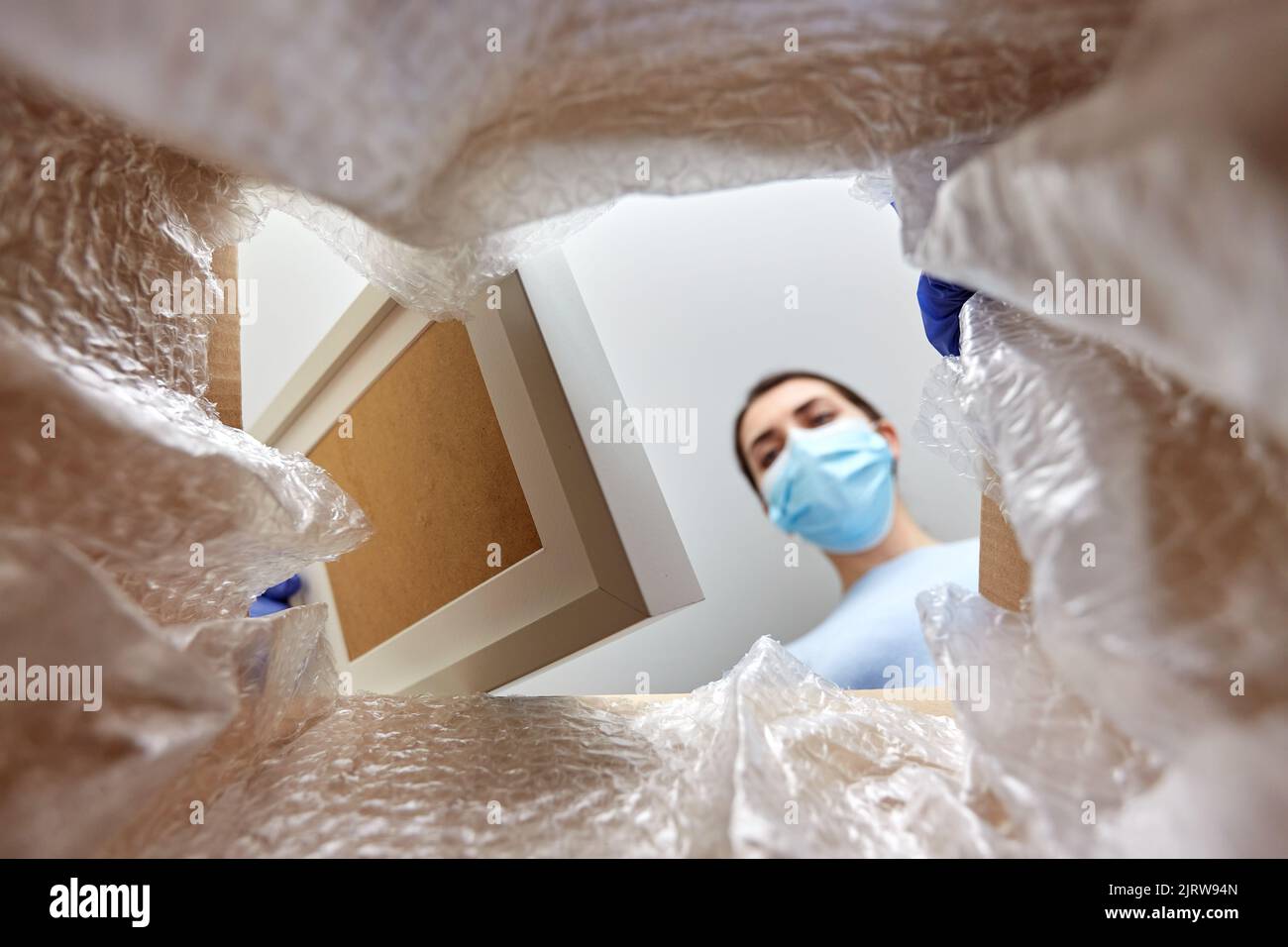 woman in mask opening parcel box with photo frame Stock Photo - Alamy