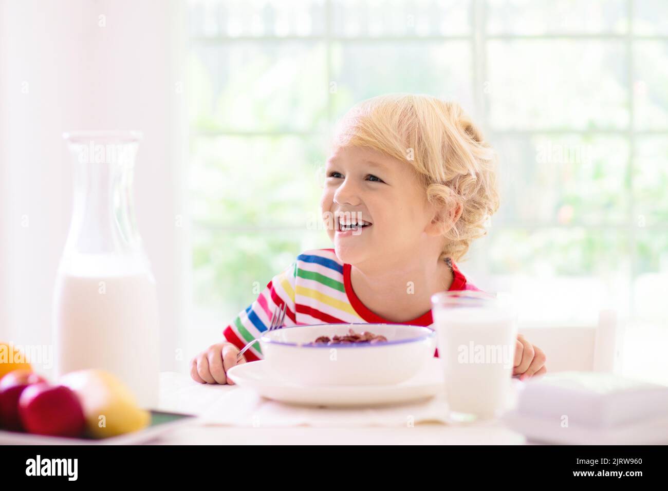 Child having breakfast. Kid drinking milk and eating cereal with fruit ...