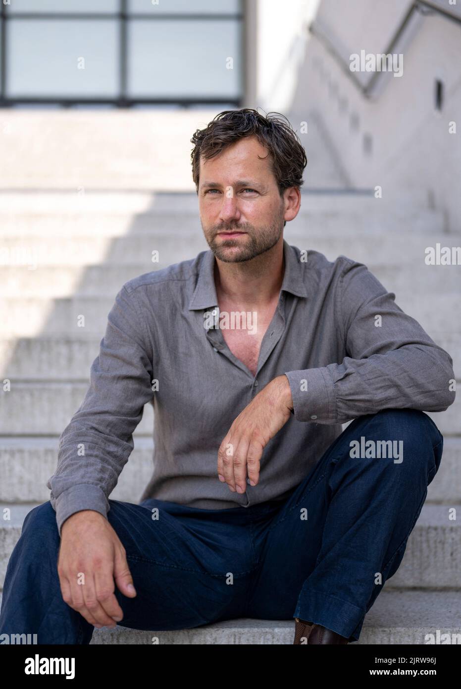 Berlin, Germany. 26th Aug, 2022. Actor Florian Stetter sits on a staircase in front of the James ...