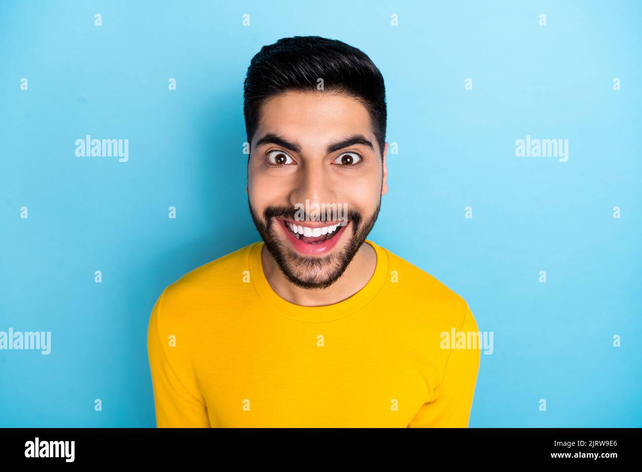 Photo of funky excited young indian guy dressed yellow pullover smiling isolated blue color ...