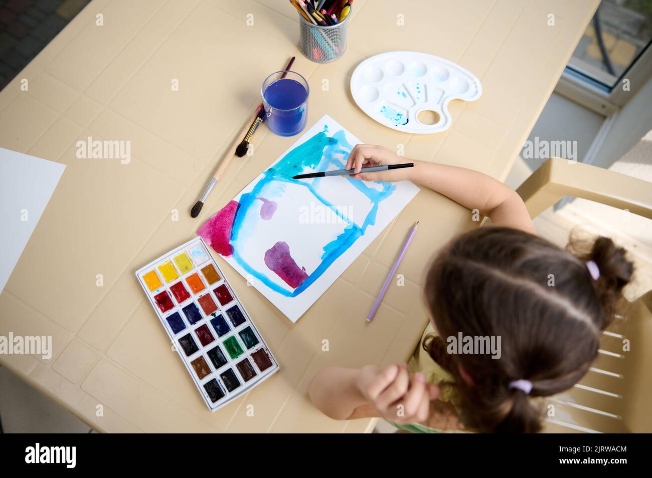 View from above of a little girl, talented child drawing picture with a ...