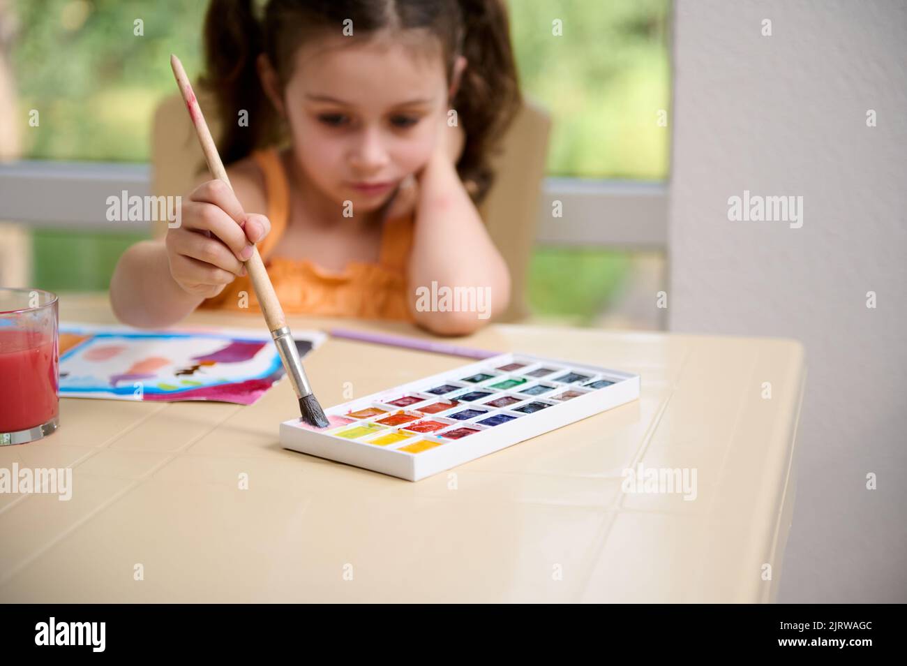 Details: little girl's hand holds a paintbrush and mixes paints on a ...