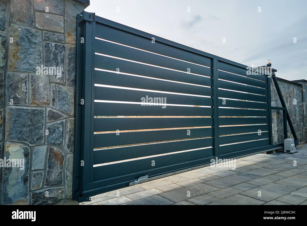 Wide automatic sliding gate with remote control installed in high stone ...