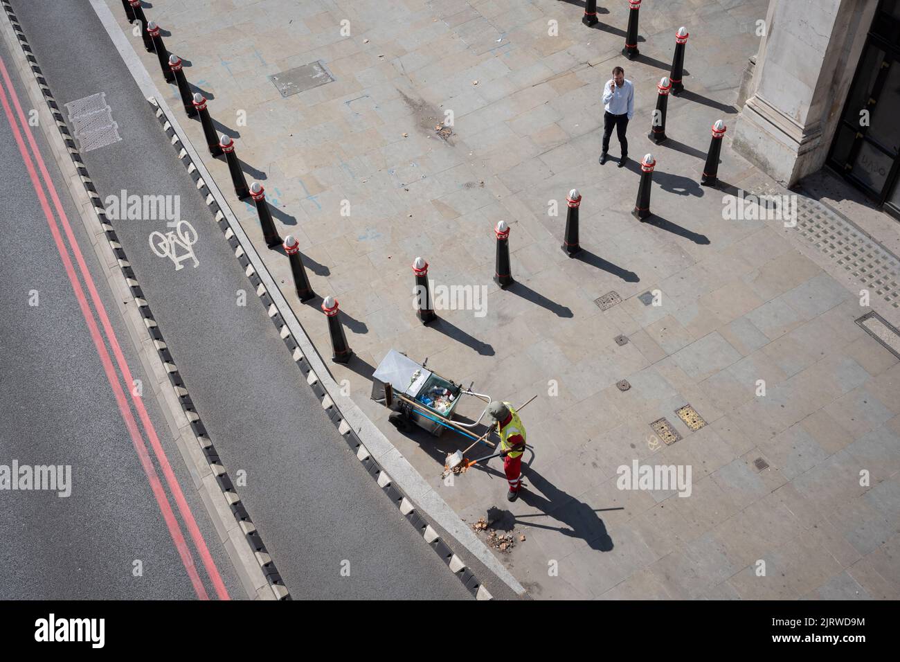 An aerial view of a street contractor removing litter along the ...