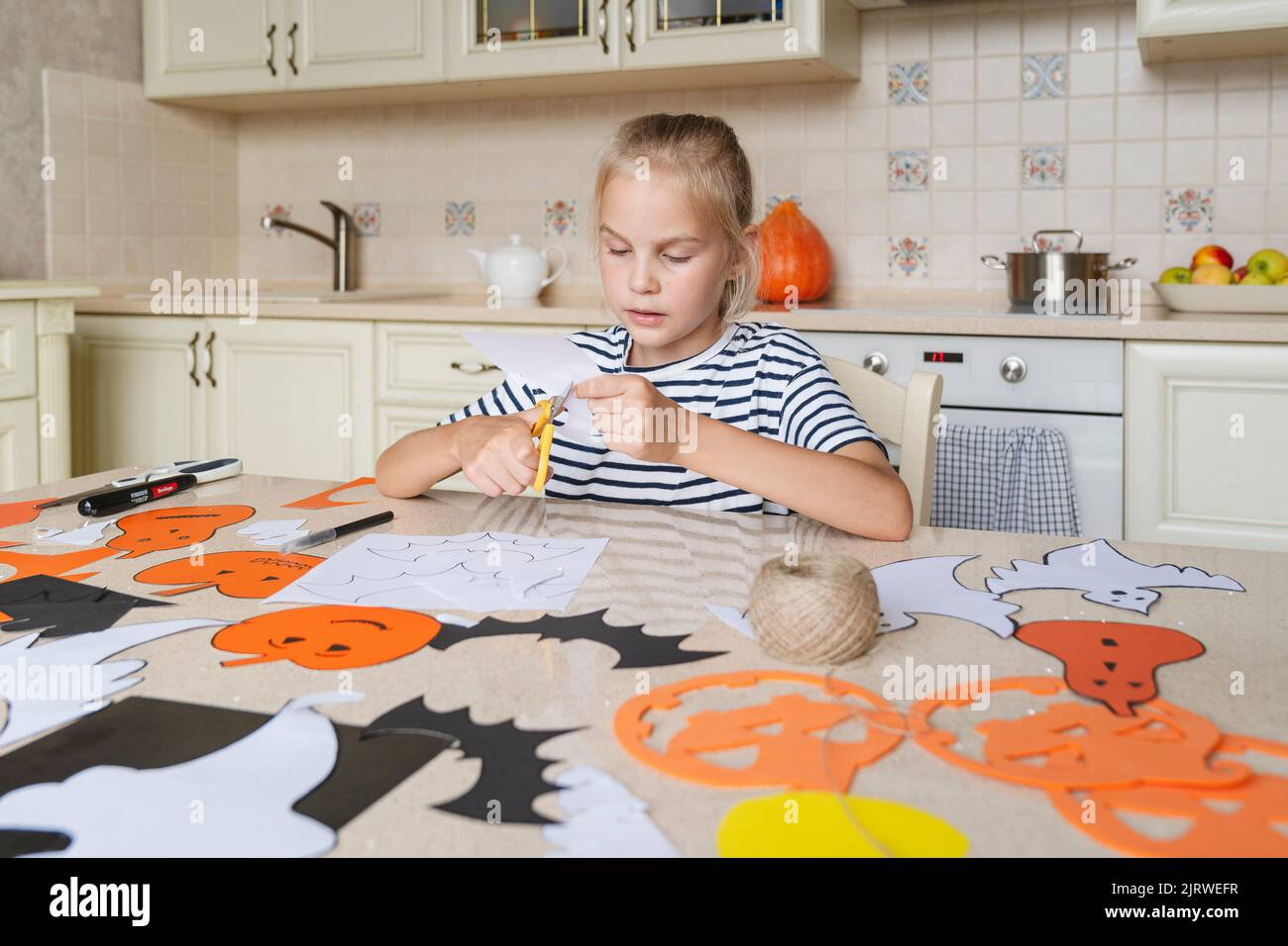 A girl cuts out paper crafts for Halloween with scissors Stock Photo ...