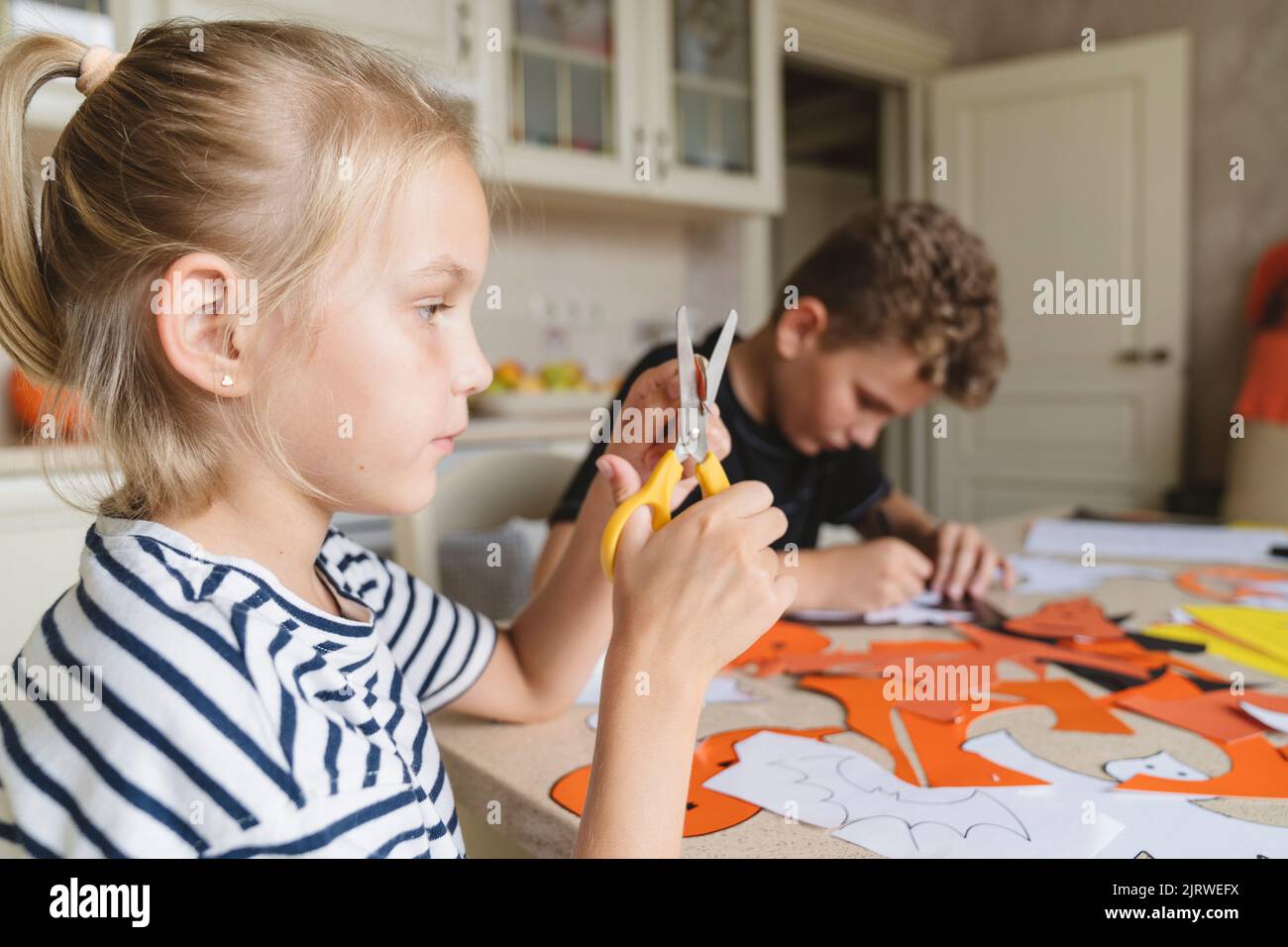 Brother and sister make crafts from colored paper for Halloween Stock ...