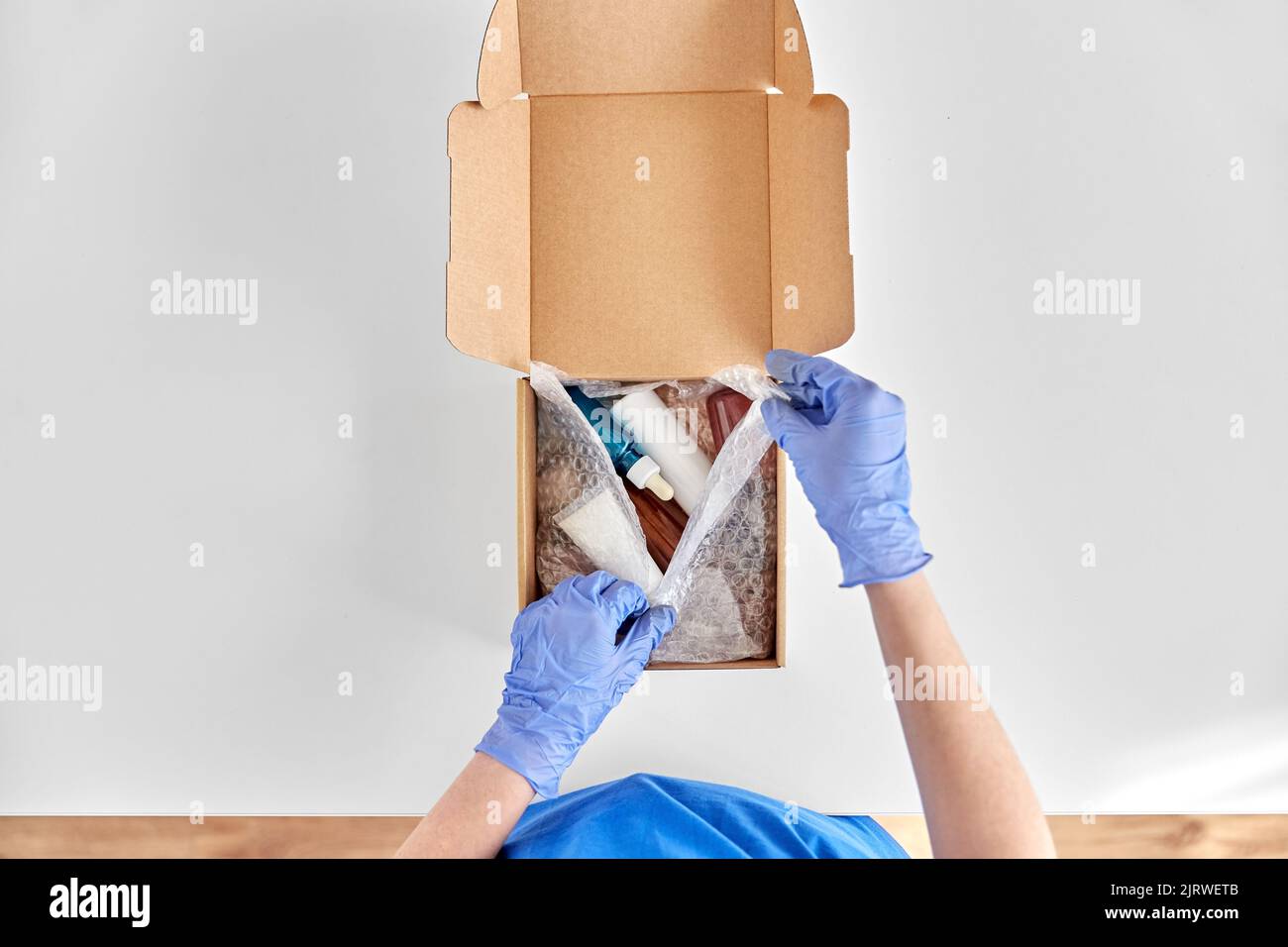 hands in gloves packing parcel box with cosmetics Stock Photo - Alamy