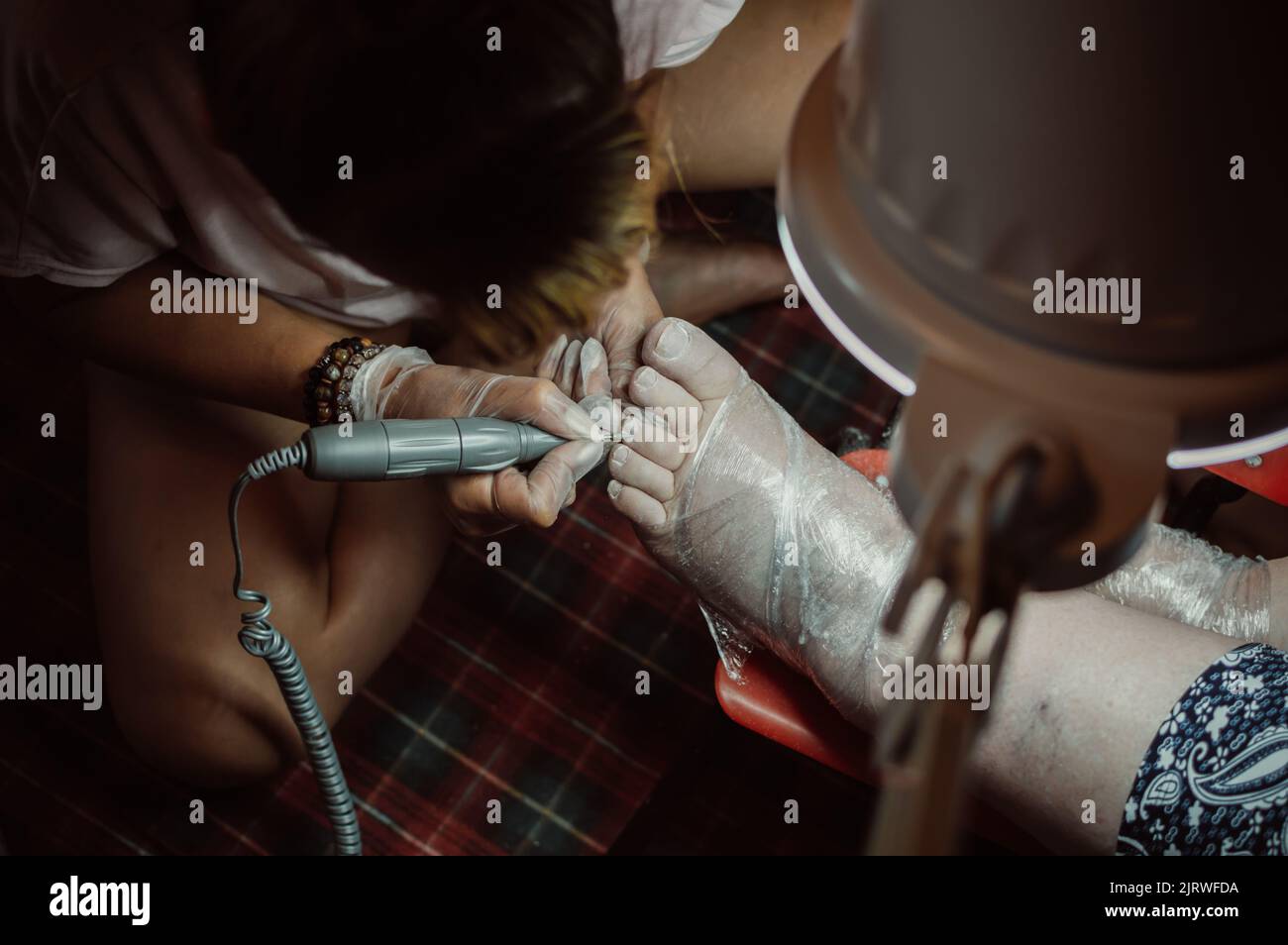 Pedicurist polishing nails with electric pedicure machine Stock Photo ...