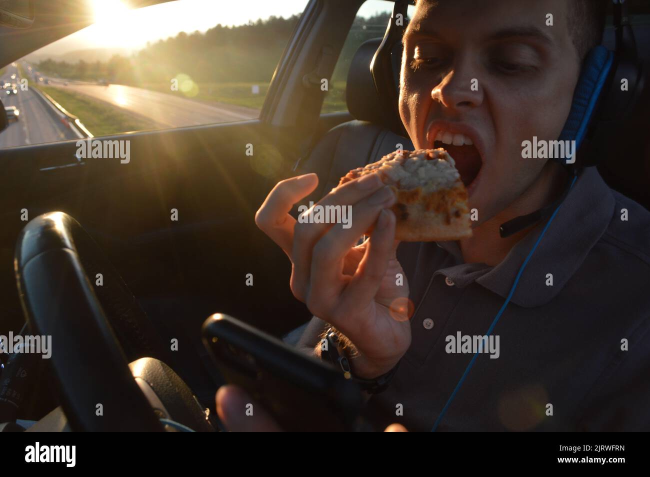 Distracted driving, eating & using phone while driving Stock Photo - Alamy