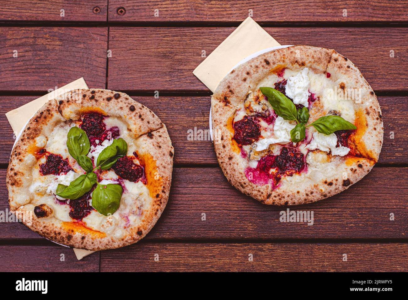 Two small crust pizzas topped with raspberry on bench Stock Photo - Alamy