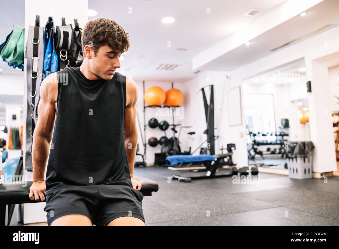 Male athlete in black activewear doing reverse push ups on bench during ...