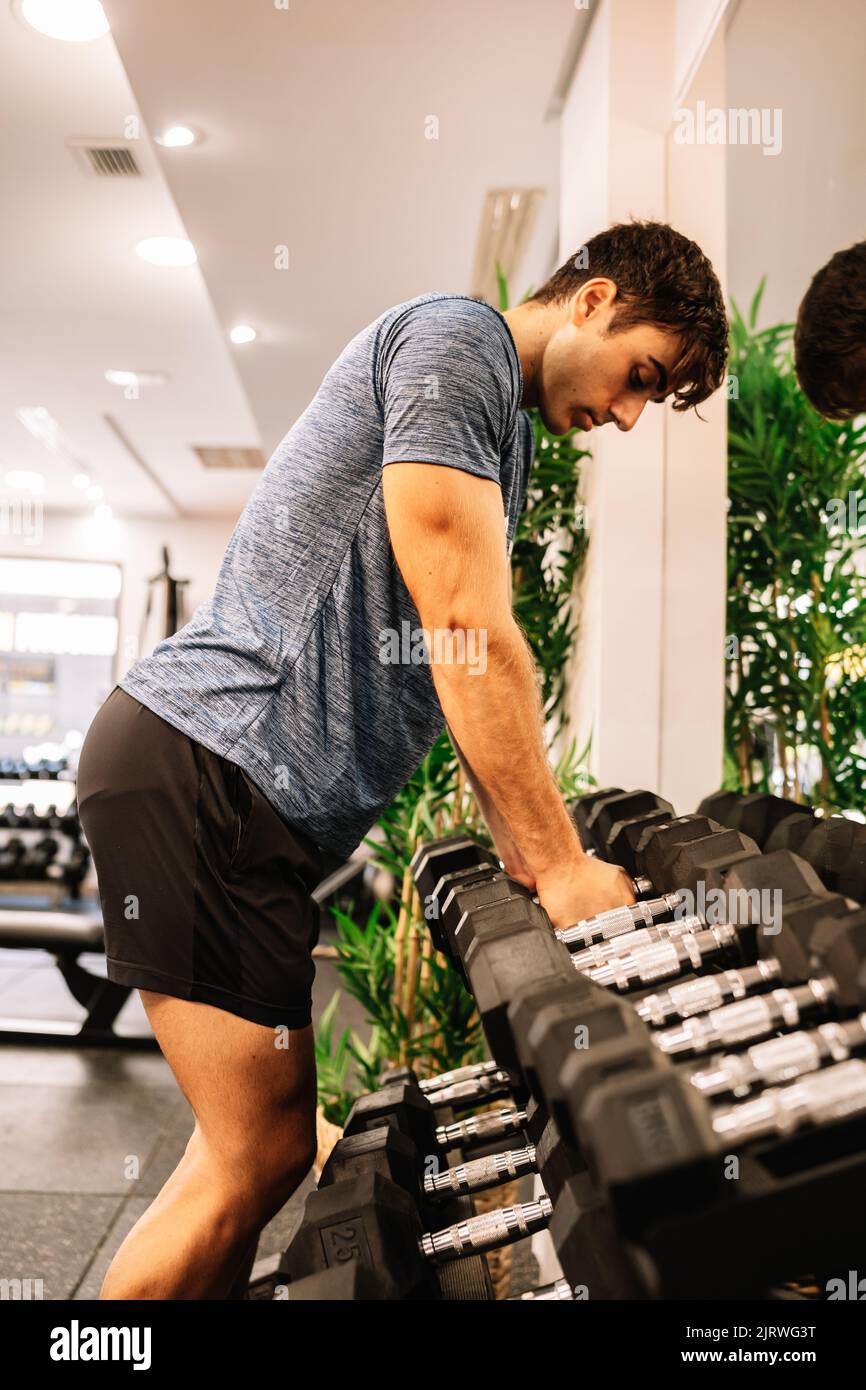 Side view of strong sportsman in t shirt and shorts taking heavy ...