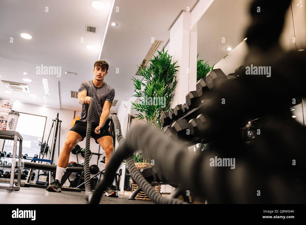 Low angle of strong male athlete in activewear doing exercise with ...