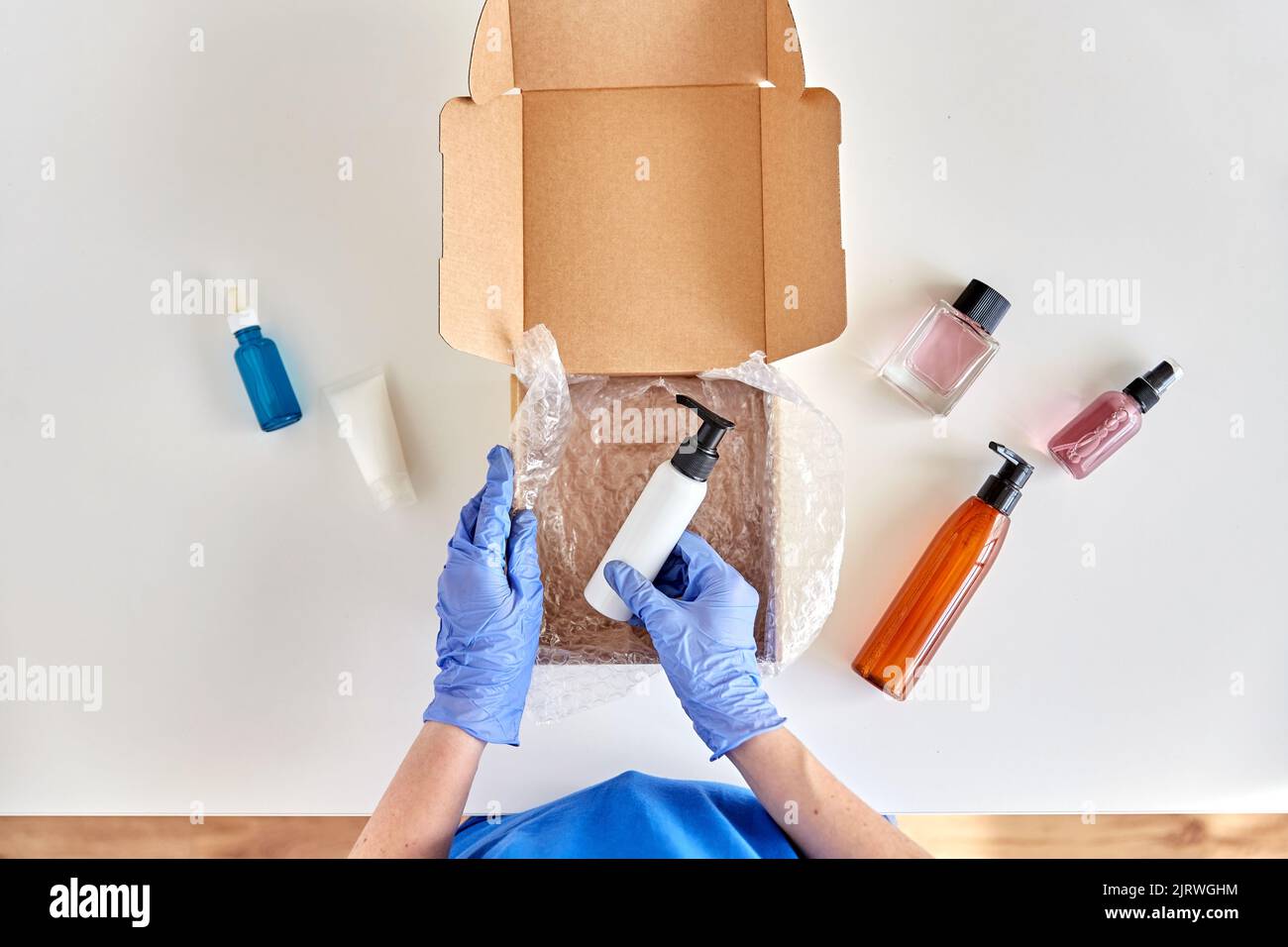 hands in gloves packing parcel box with cosmetics Stock Photo - Alamy