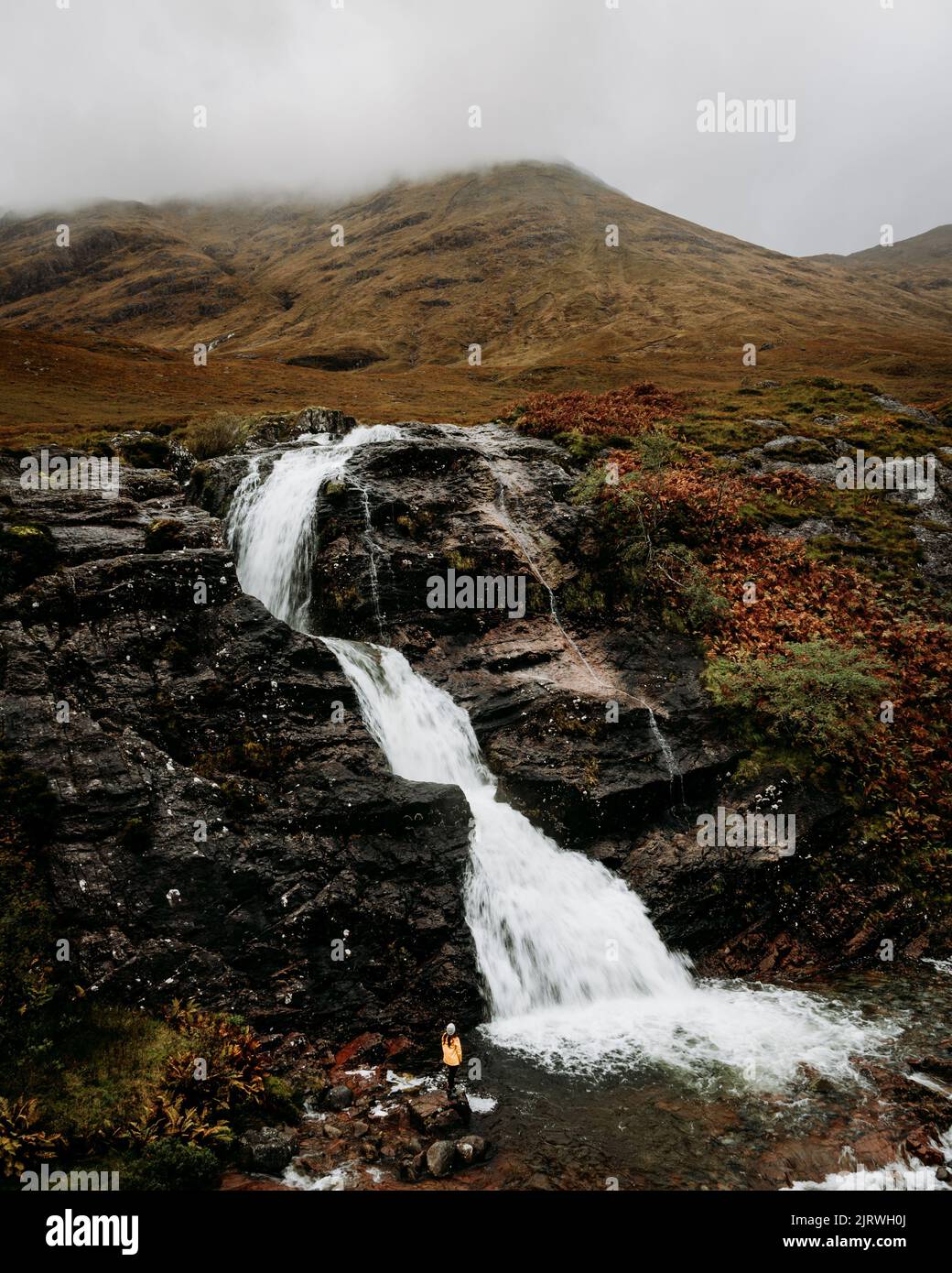 The beautiful vertical view of the waterfall flowing over the rocky ...