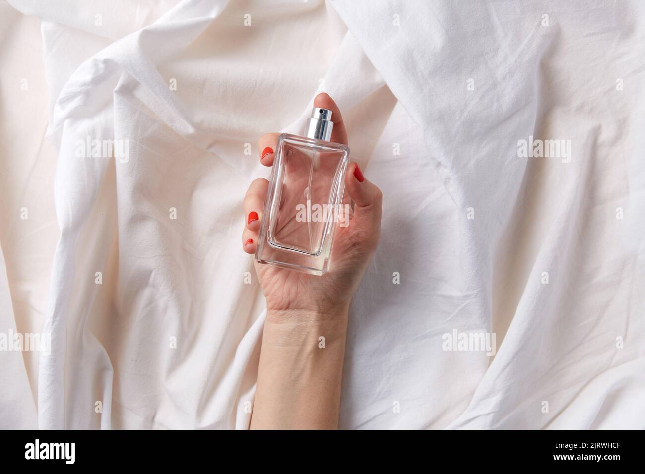 female hand with bottle of perfume on white sheet Stock Photo - Alamy