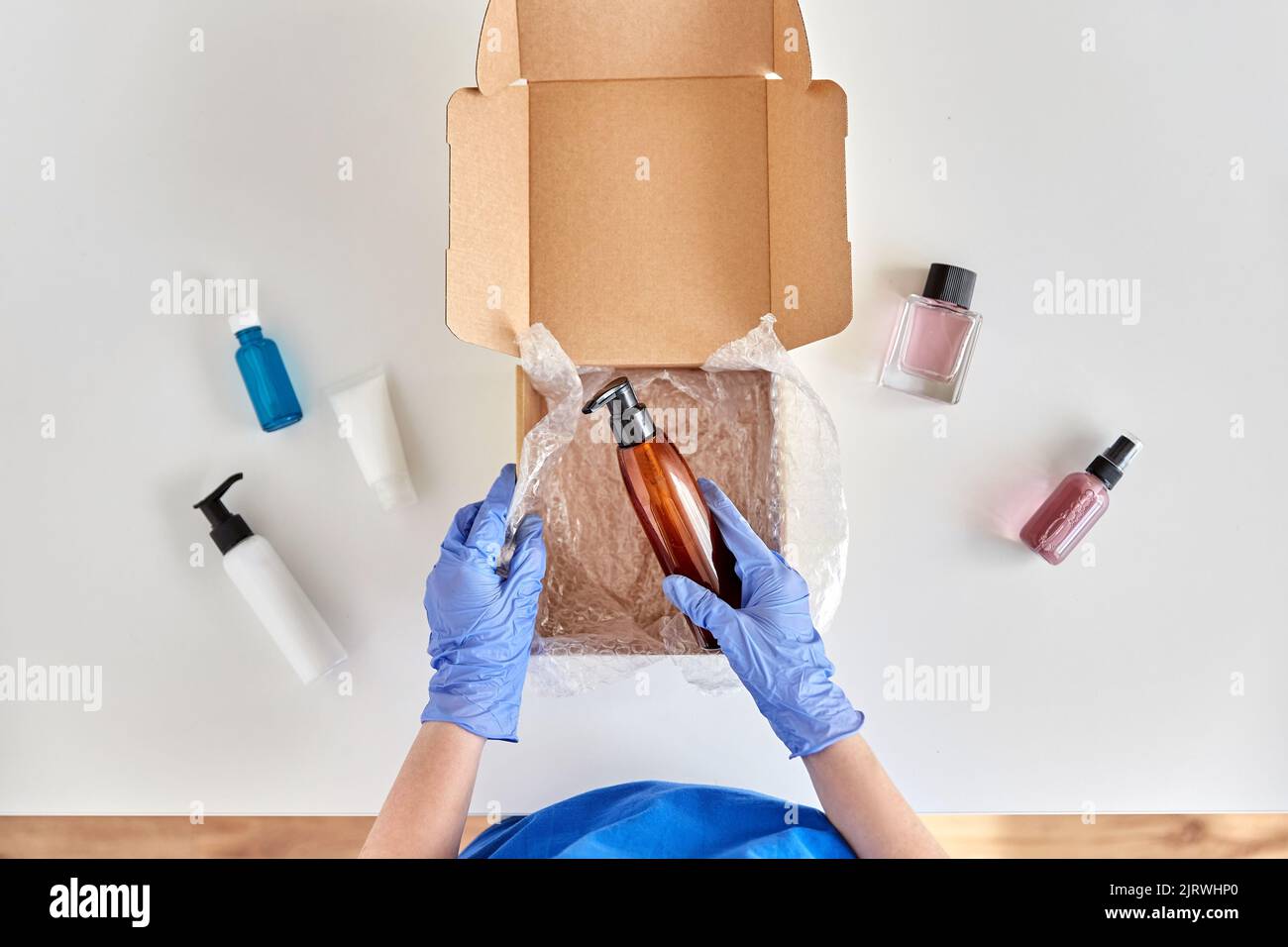 hands in gloves packing parcel box with cosmetics Stock Photo - Alamy