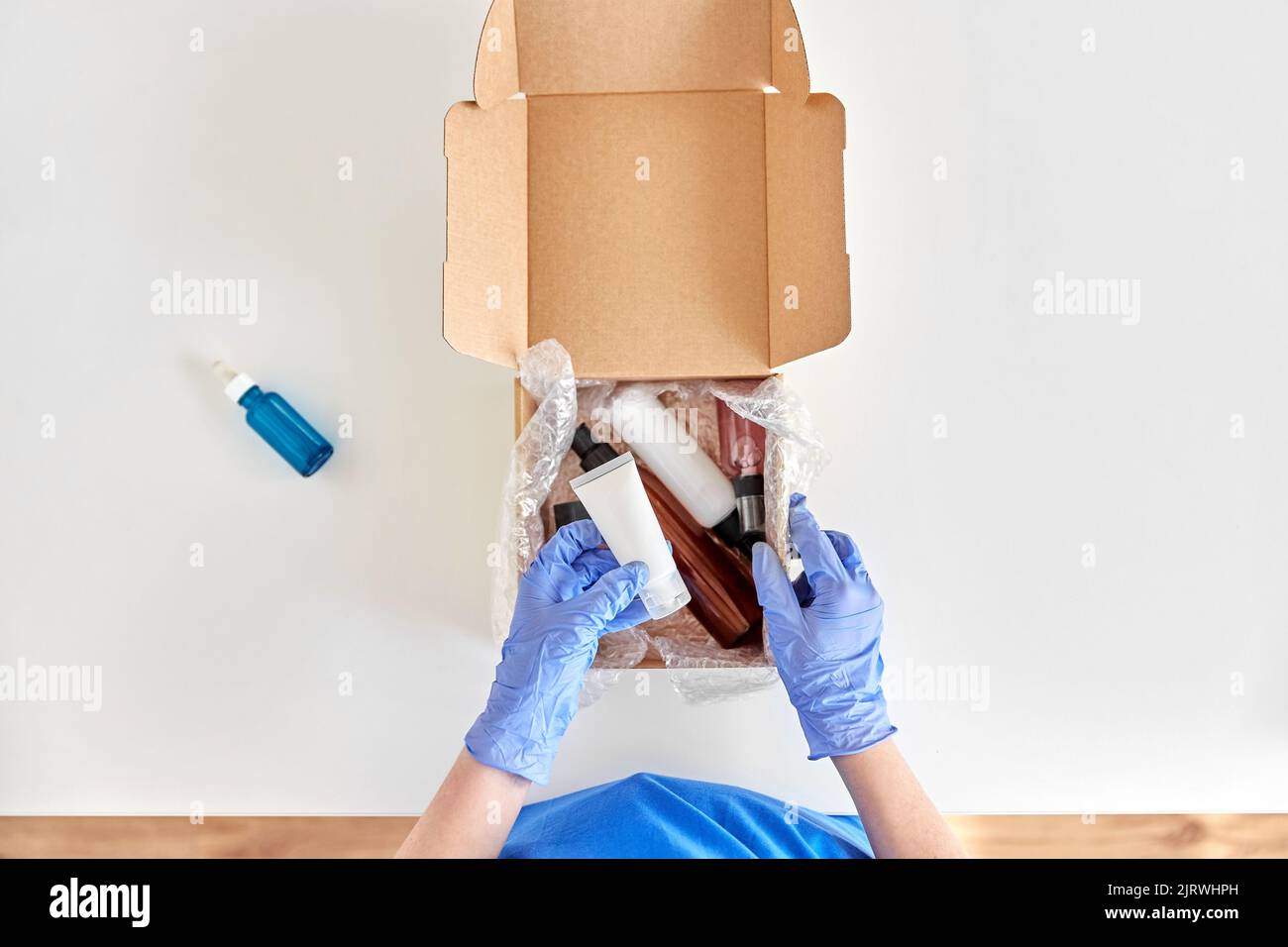 hands in gloves packing parcel box with cosmetics Stock Photo - Alamy