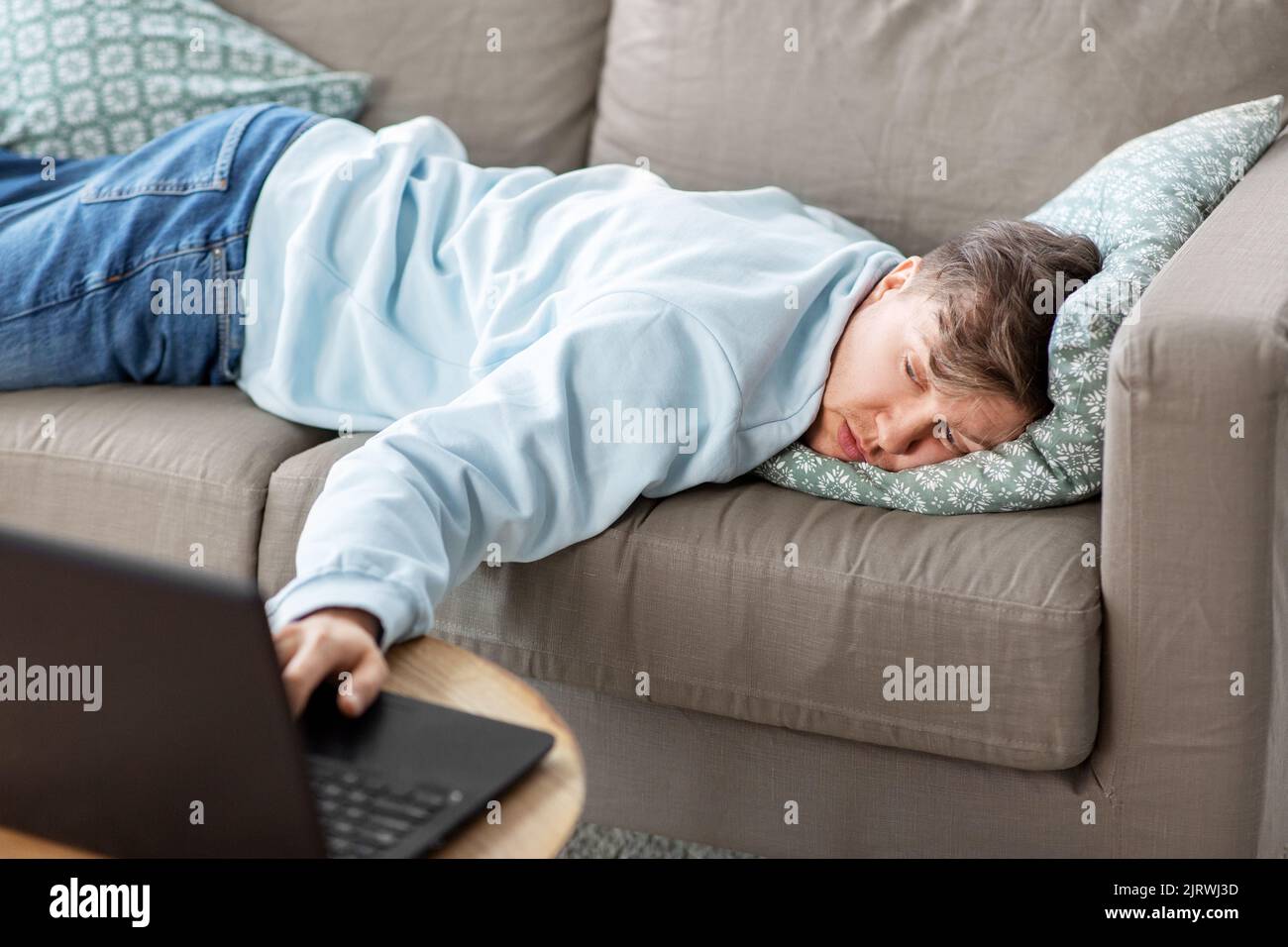 bored man with laptop lying on sofa at home Stock Photo - Alamy