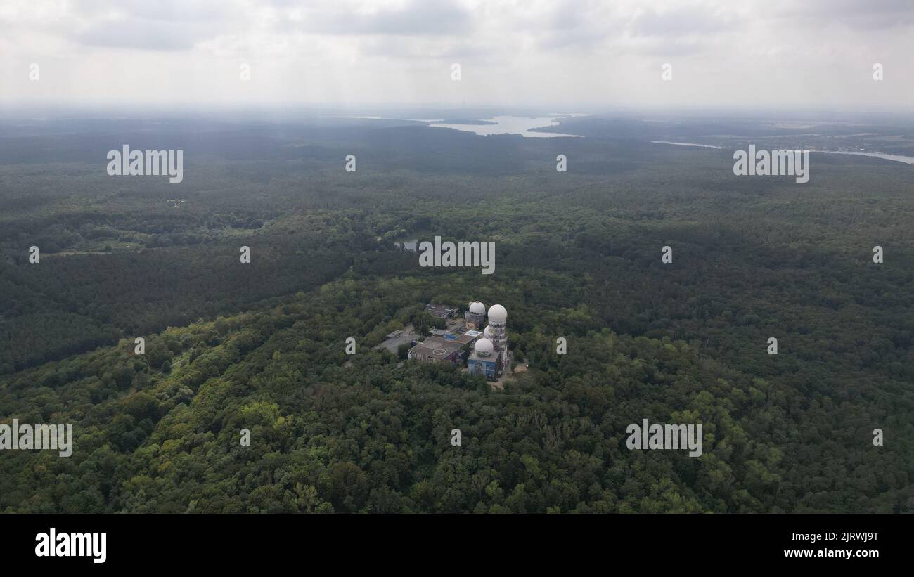 An aerial view of Teufelsberg surrounded by lush trees with a sky ...