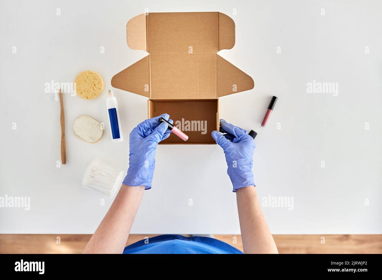 hands in gloves packing parcel box with cosmetics Stock Photo - Alamy