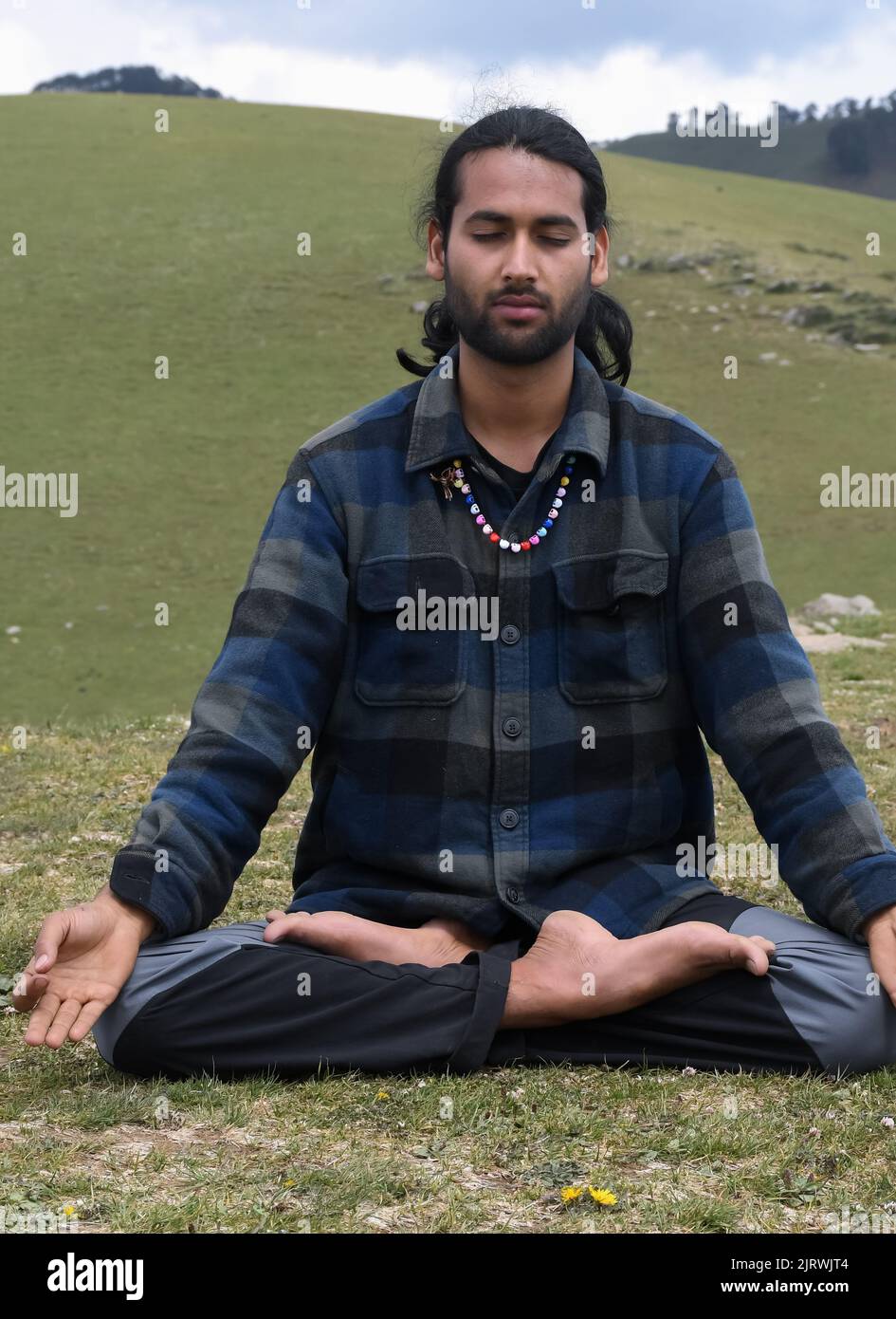 Front view of a good looking Indian young man practicing Yoga in Lotus ...
