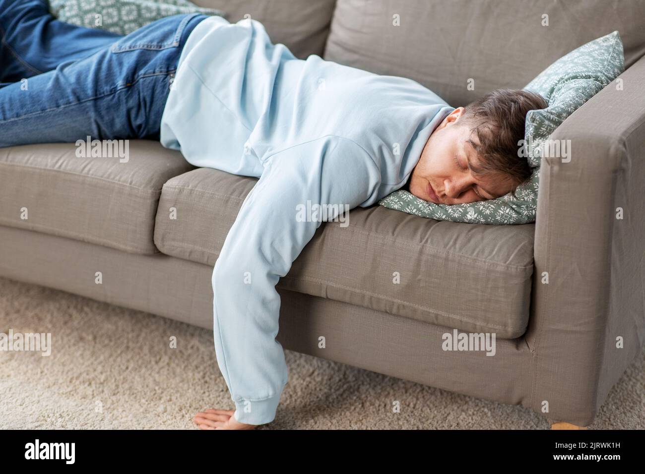 young man sleeping on sofa at home Stock Photo - Alamy