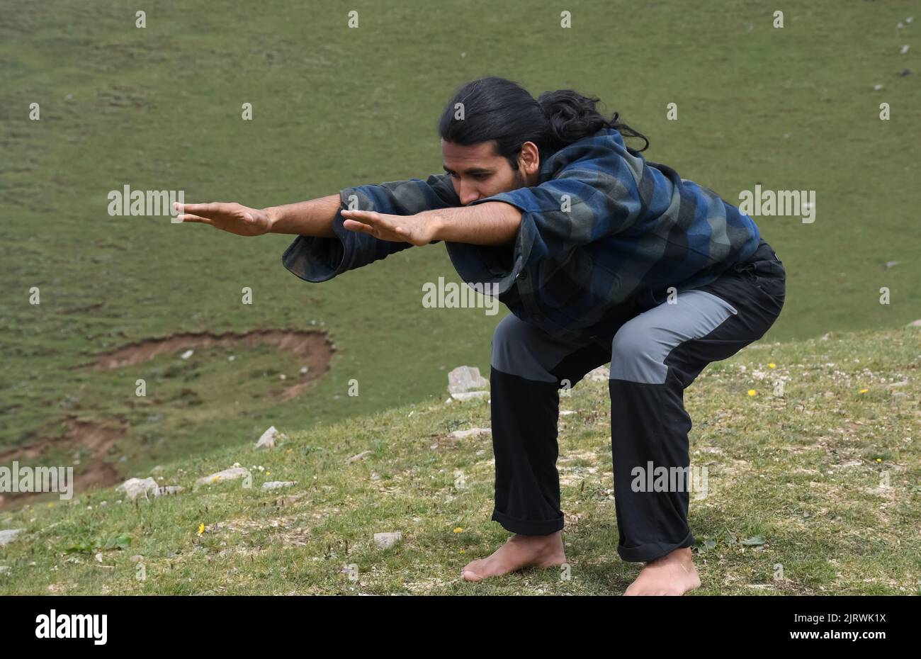A long haired Indian young man practicing Bear Pose (Chair Pose ...