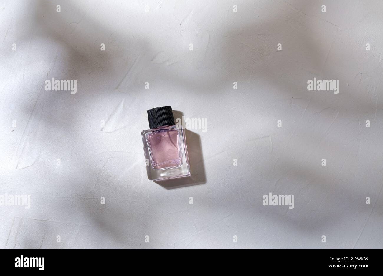 bottle of perfume on white surface with shadows Stock Photo - Alamy