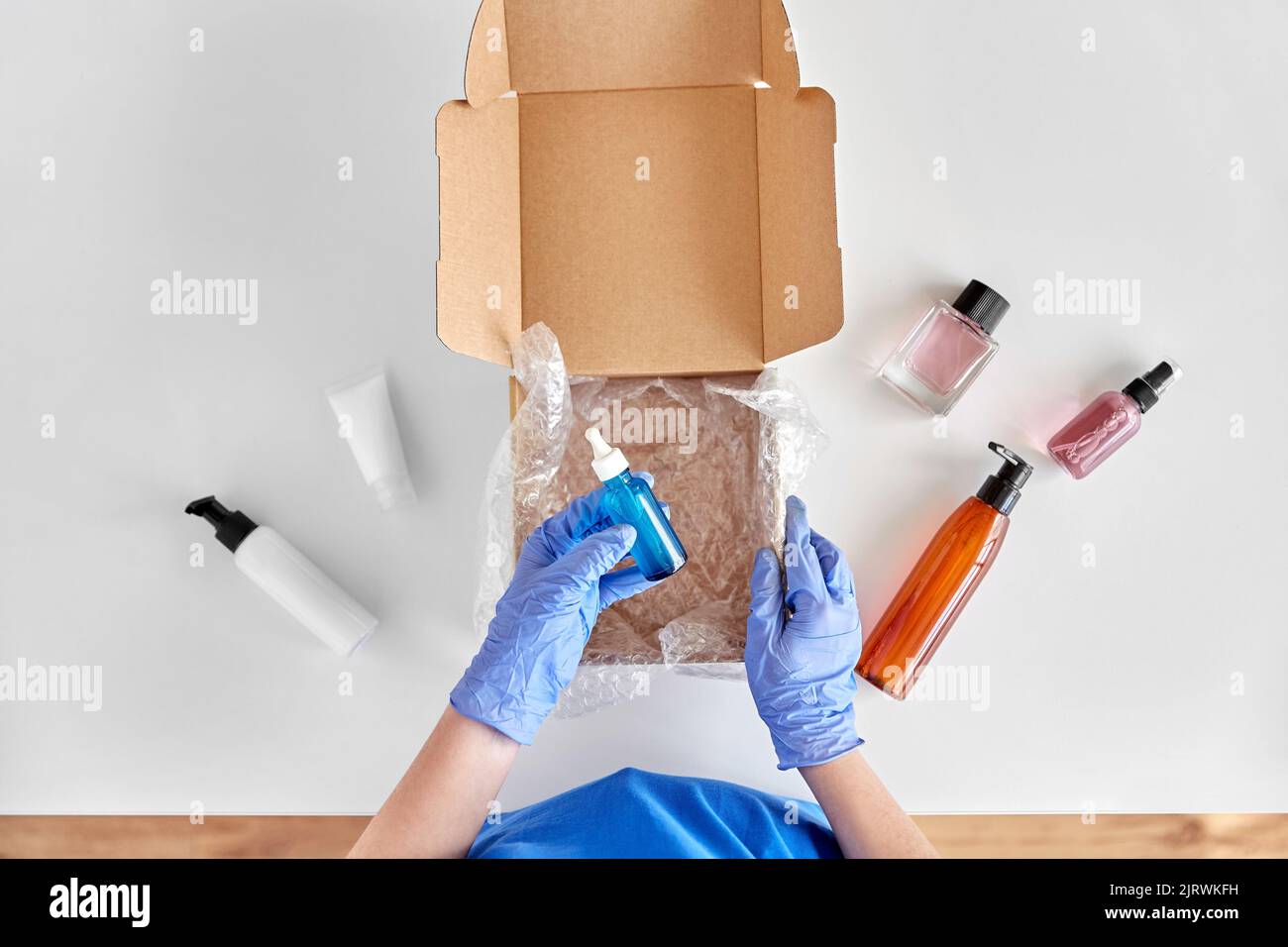 hands in gloves packing parcel box with cosmetics Stock Photo - Alamy