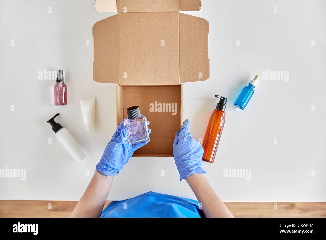 hands in gloves packing parcel box with cosmetics Stock Photo - Alamy