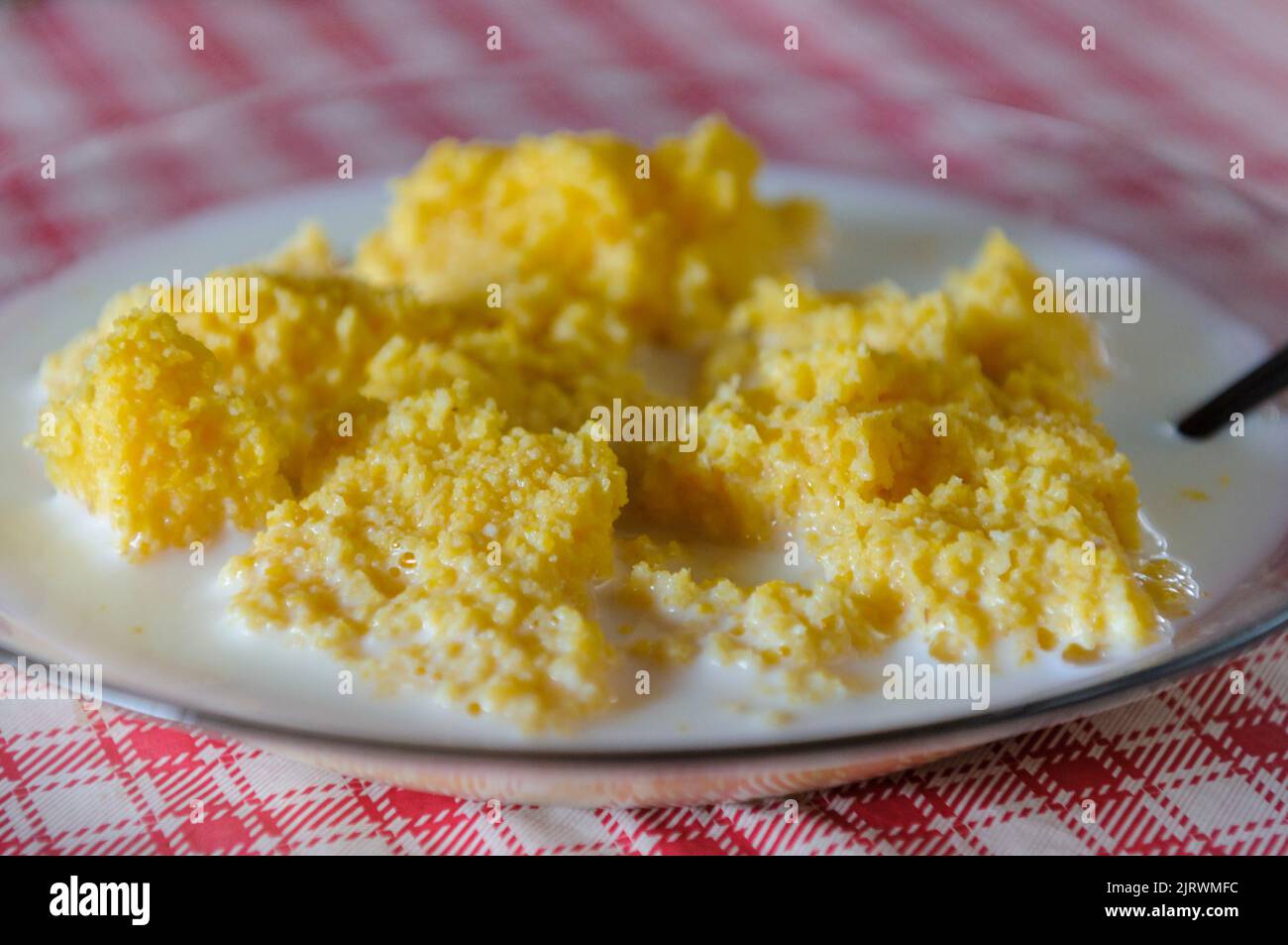 Corn couscous with milk on table with red and white tablecloth. Popular ...