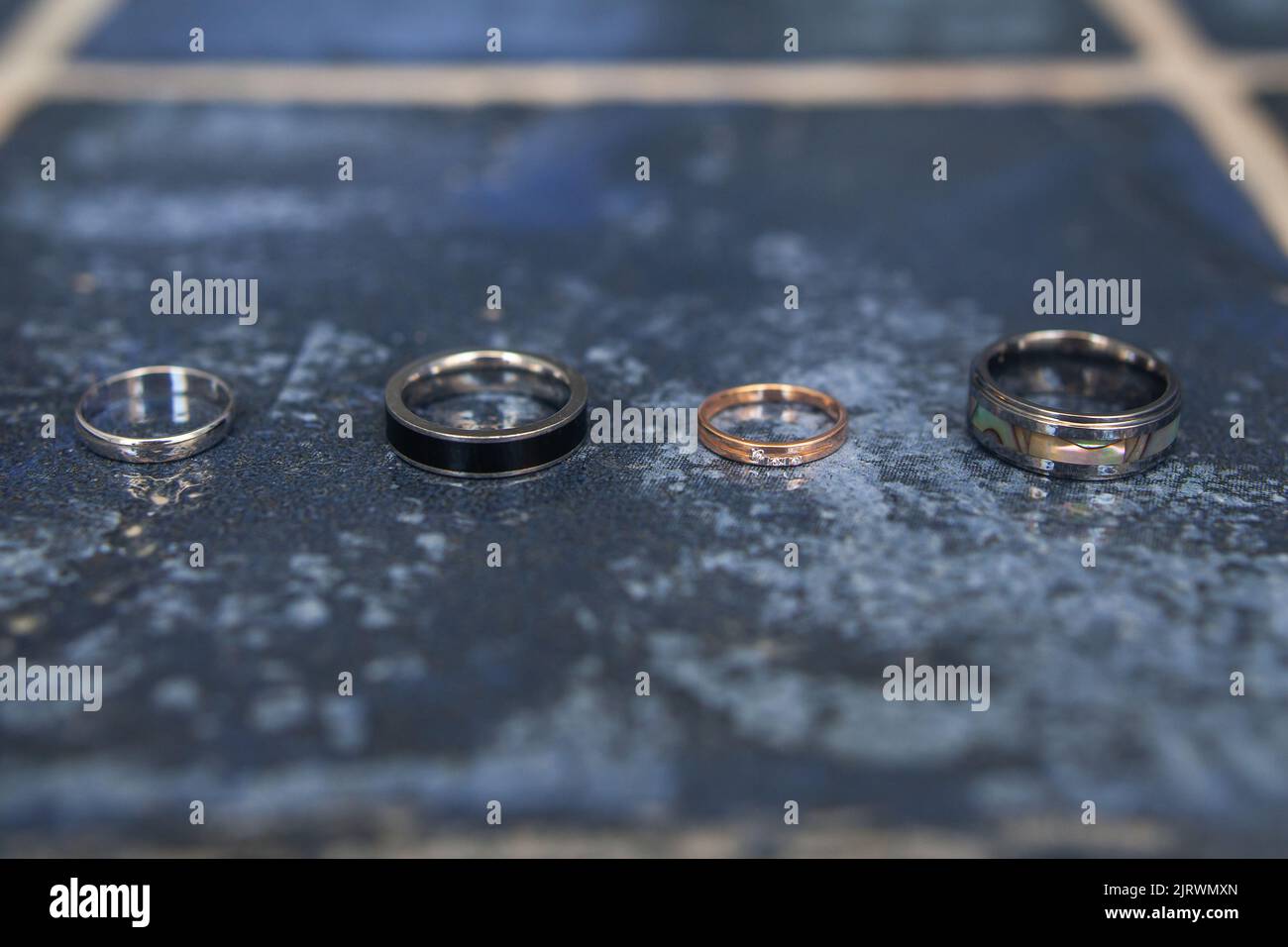 Four wedding rings on a blue tile Stock Photo - Alamy