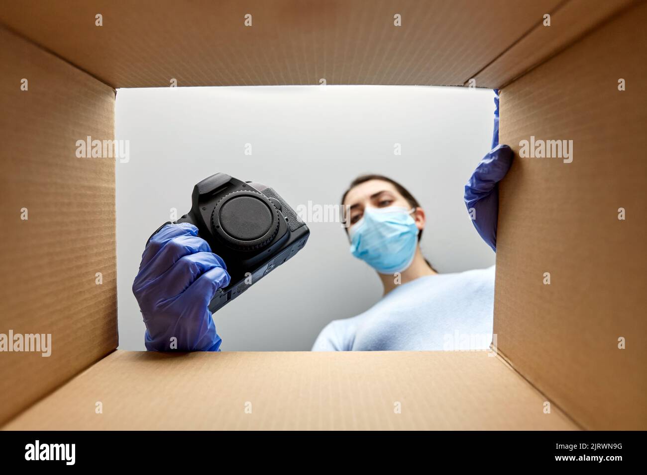 woman in mask packing camera into parcel box Stock Photo - Alamy