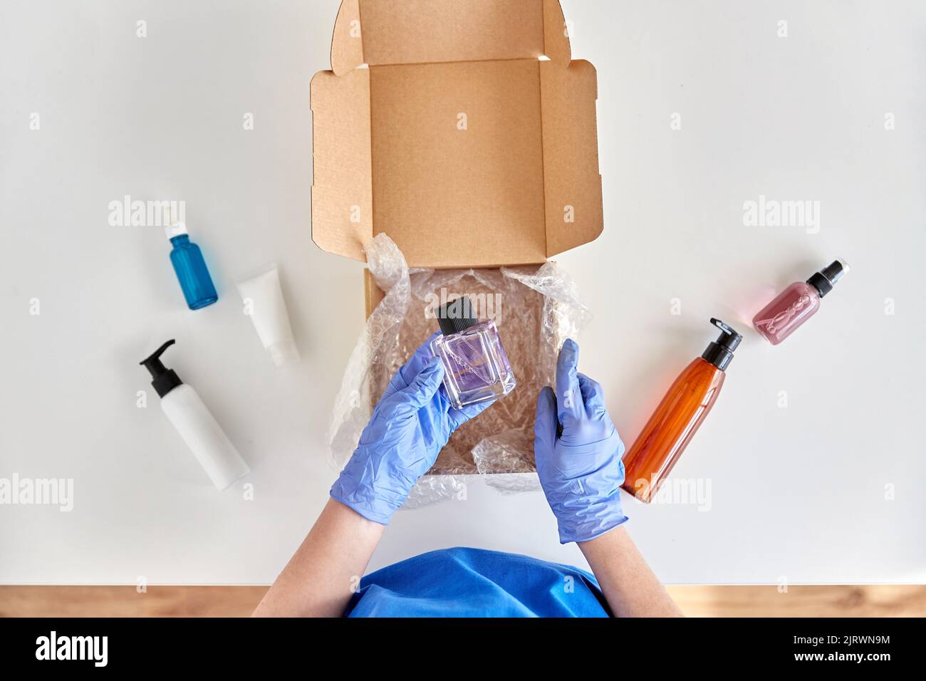 hands in gloves packing parcel box with cosmetics Stock Photo - Alamy