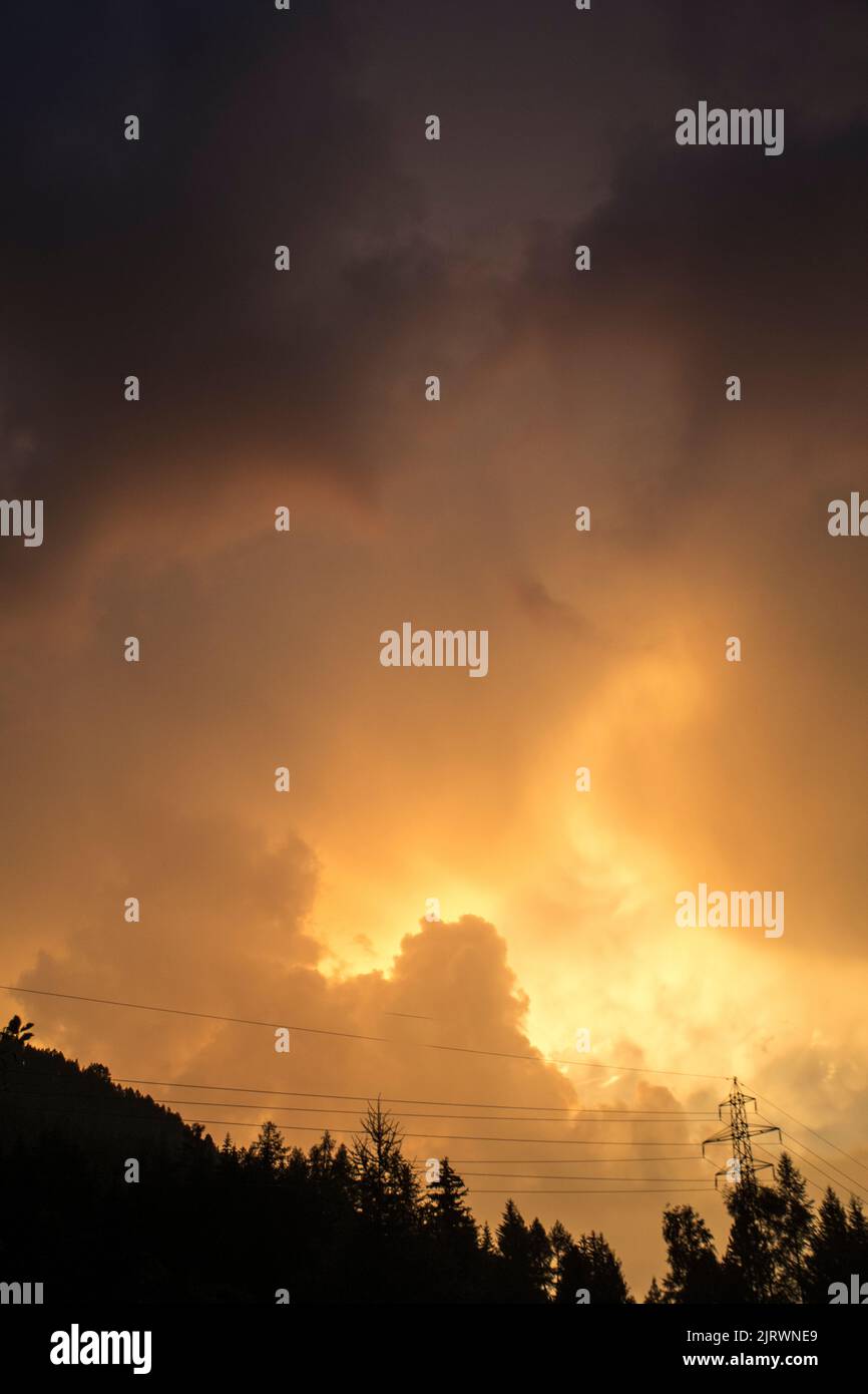 Golden light in a cloudy sky after a storm. Electricity pylons are ...