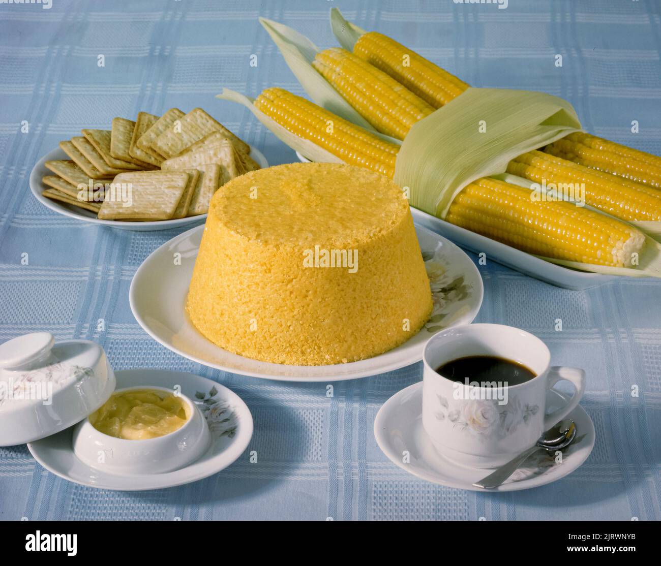 Corn couscous at the table with a cup of coffee and boiled corn cobs ...