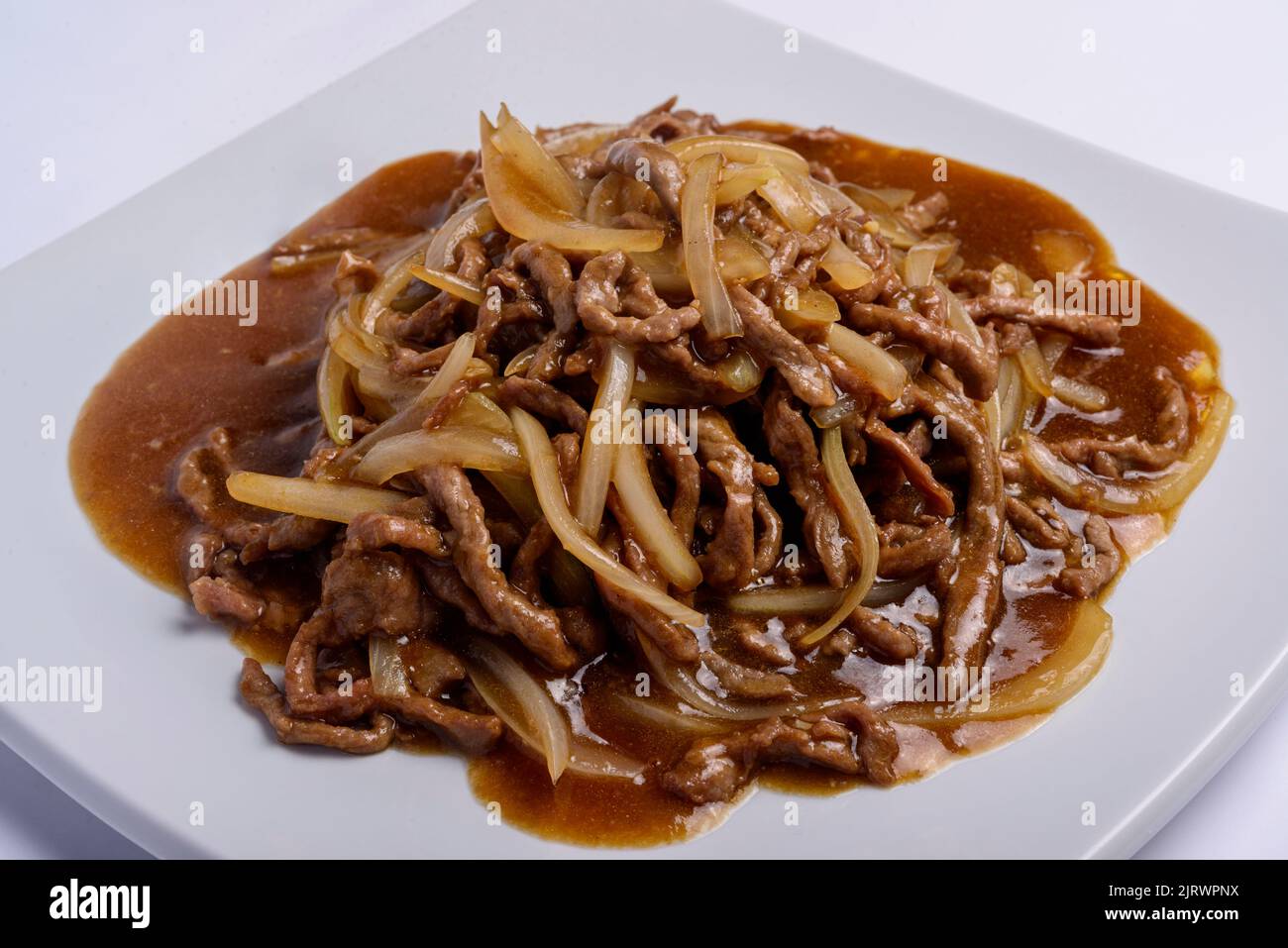 Shredded beef with onion on white square plate. Brazilian-style Chinese ...