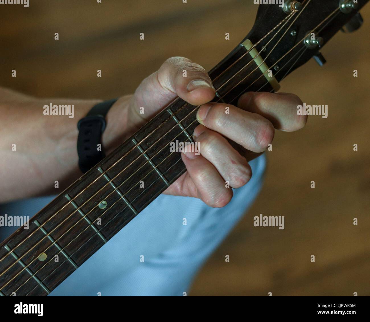 a close-up shot of an acoustic guitar fretboard with male fingers hand ...