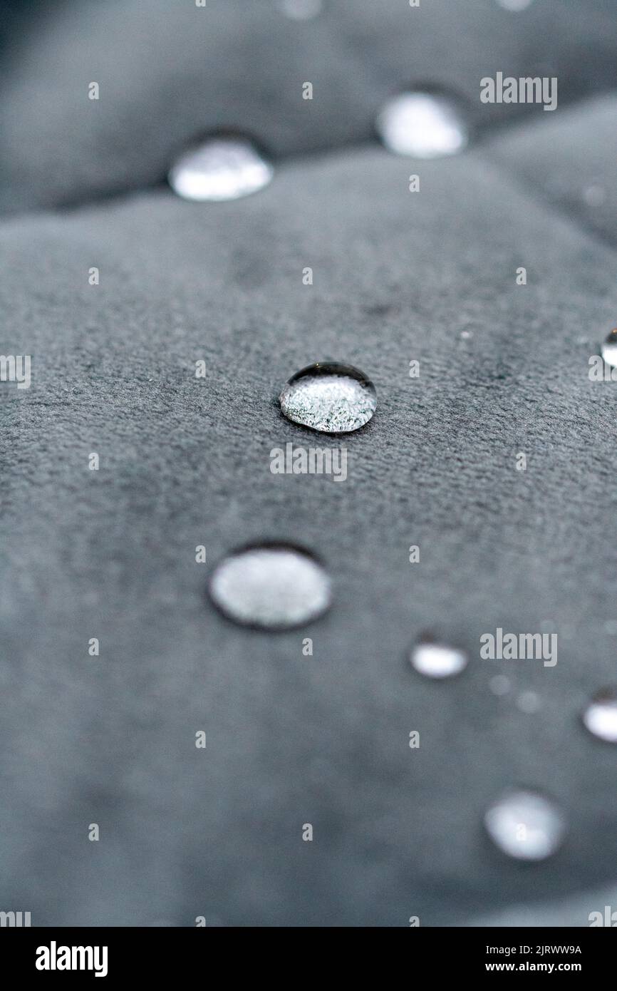 Closeup or macro of a small water drop on water repellent fabric or ...