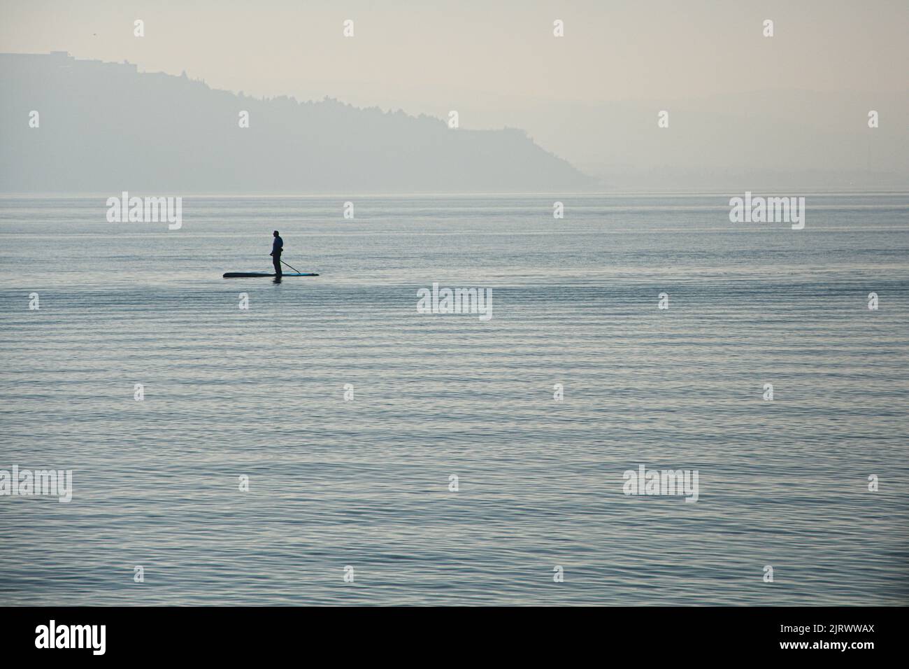 silhouette of person paddling on a stand up paddle board (SUP Stock ...