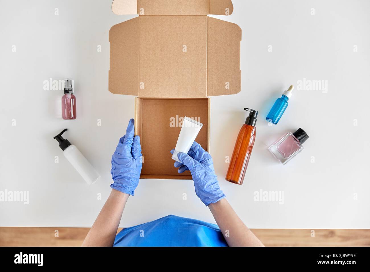 hands in gloves packing parcel box with cosmetics Stock Photo - Alamy
