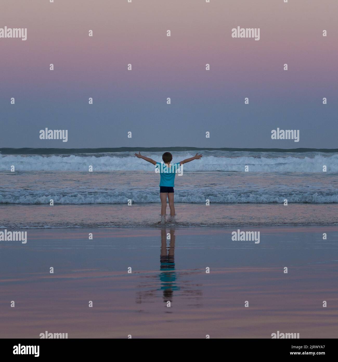 boy from behind with raised hands on a beach at sunset Stock Photo - Alamy