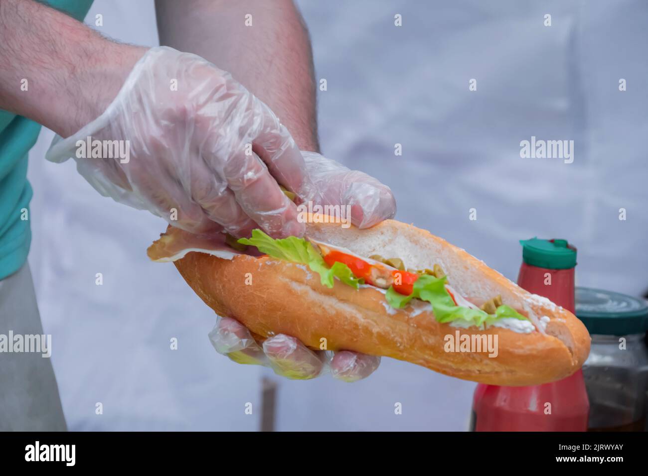 Chef hands making fresh submarine hotdog sandwiche at food market ...