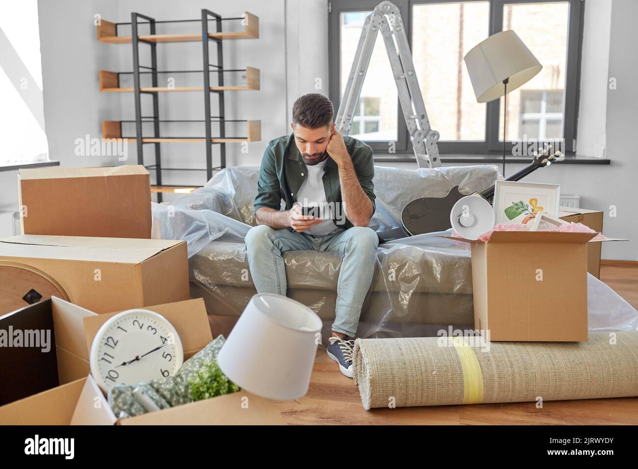 sad man with smartphone and boxes moving home Stock Photo - Alamy