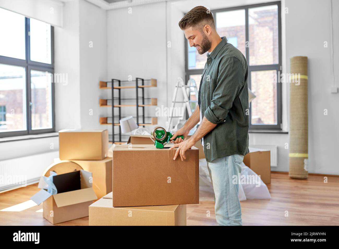 man with adhesive tape packing box at new home Stock Photo - Alamy
