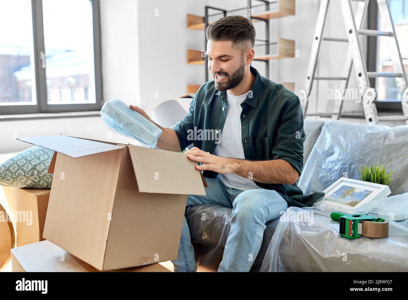 happy man unpacking boxes and moving to new home Stock Photo - Alamy