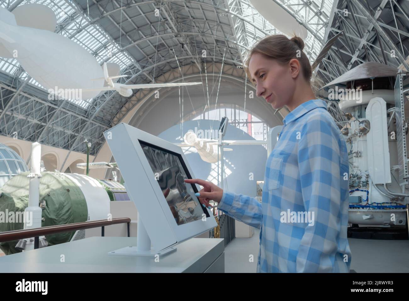 Side view: woman touching interactive touchscreen display kiosk at ...