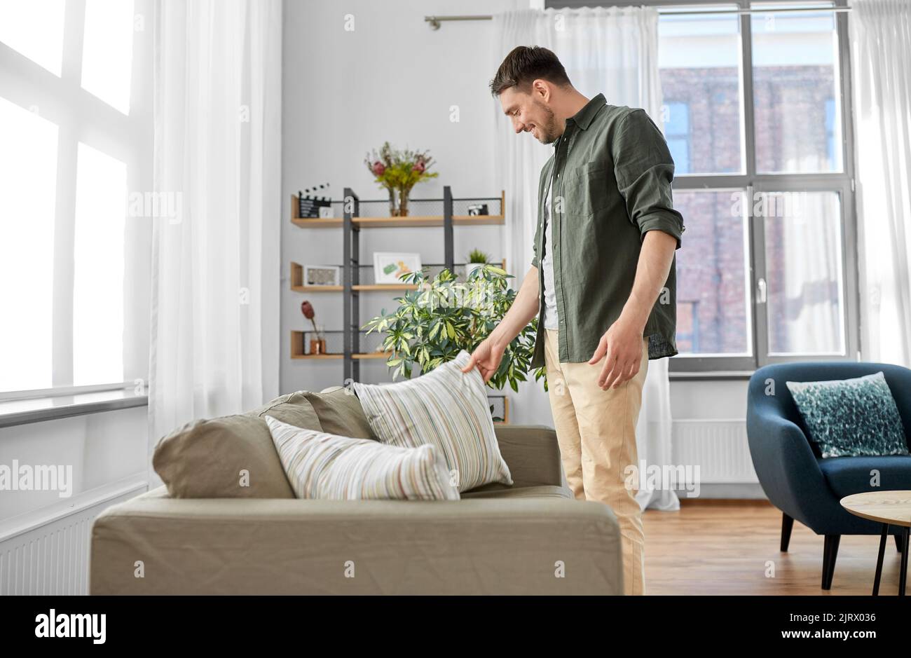 happy smiling man arranging sofa cushions at home Stock Photo - Alamy